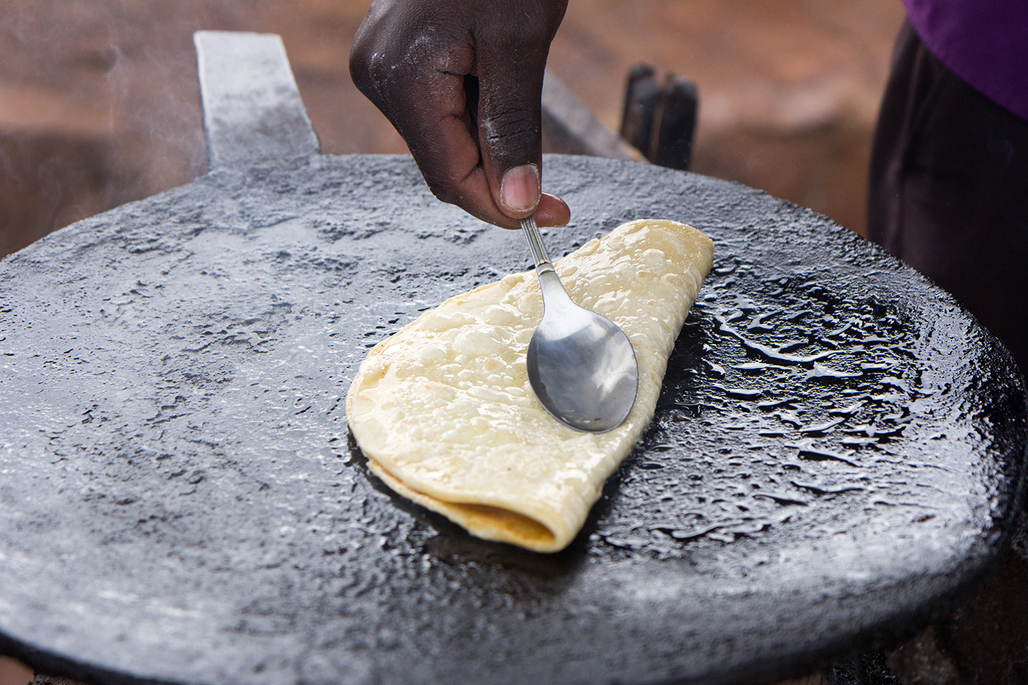 A flatbread called “chapati” being fried and folded with a spoon – The ...